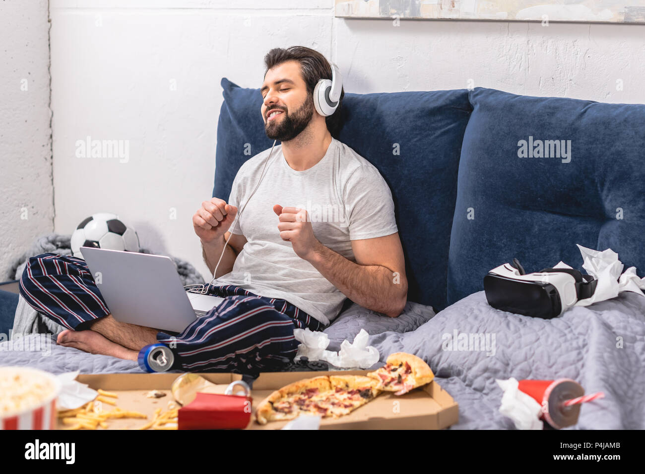 happy handsome loner listening music with laptop in bedroom Stock Photo ...