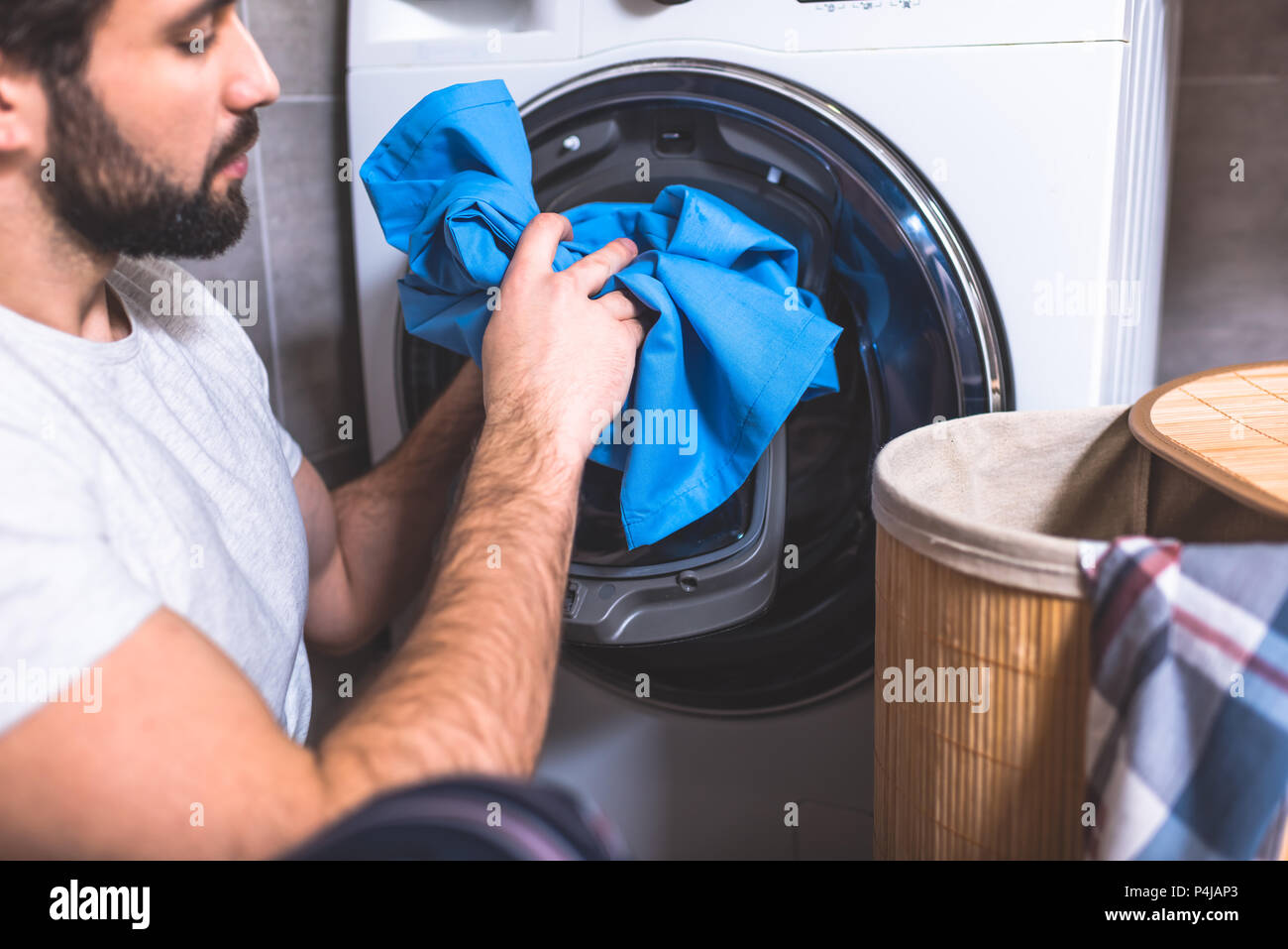 side view of loner putting laundry in washing machine in bathroom Stock ...