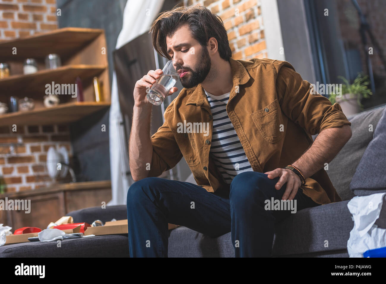 handsome loner drinking water while having hangover in morning at ...