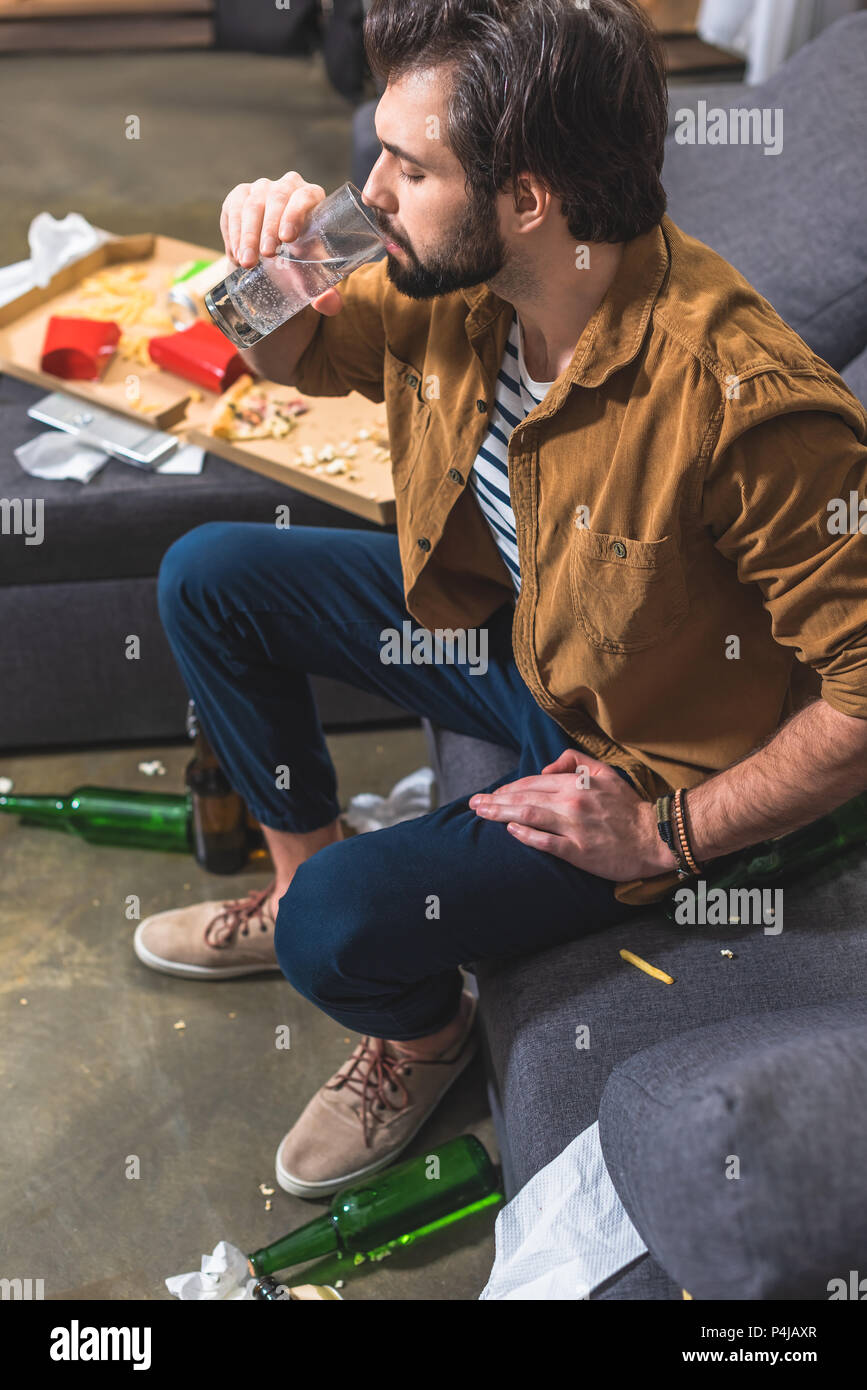 high angle view of loner drinking water and having hangover at living ...