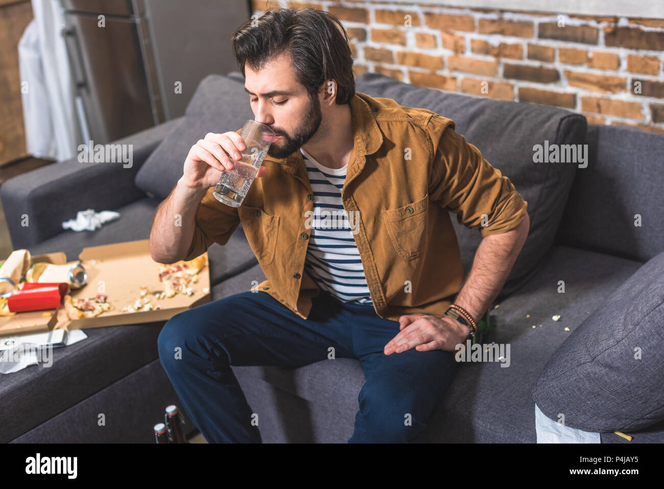 handsome loner drinking water and having hangover at living room Stock ...
