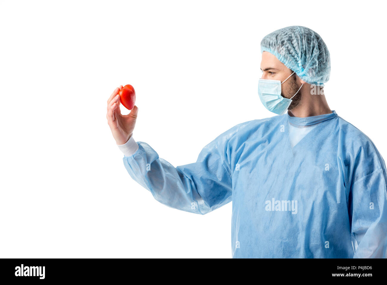 Concentrated cardiologist wearing blue uniform and holding toy heart ...