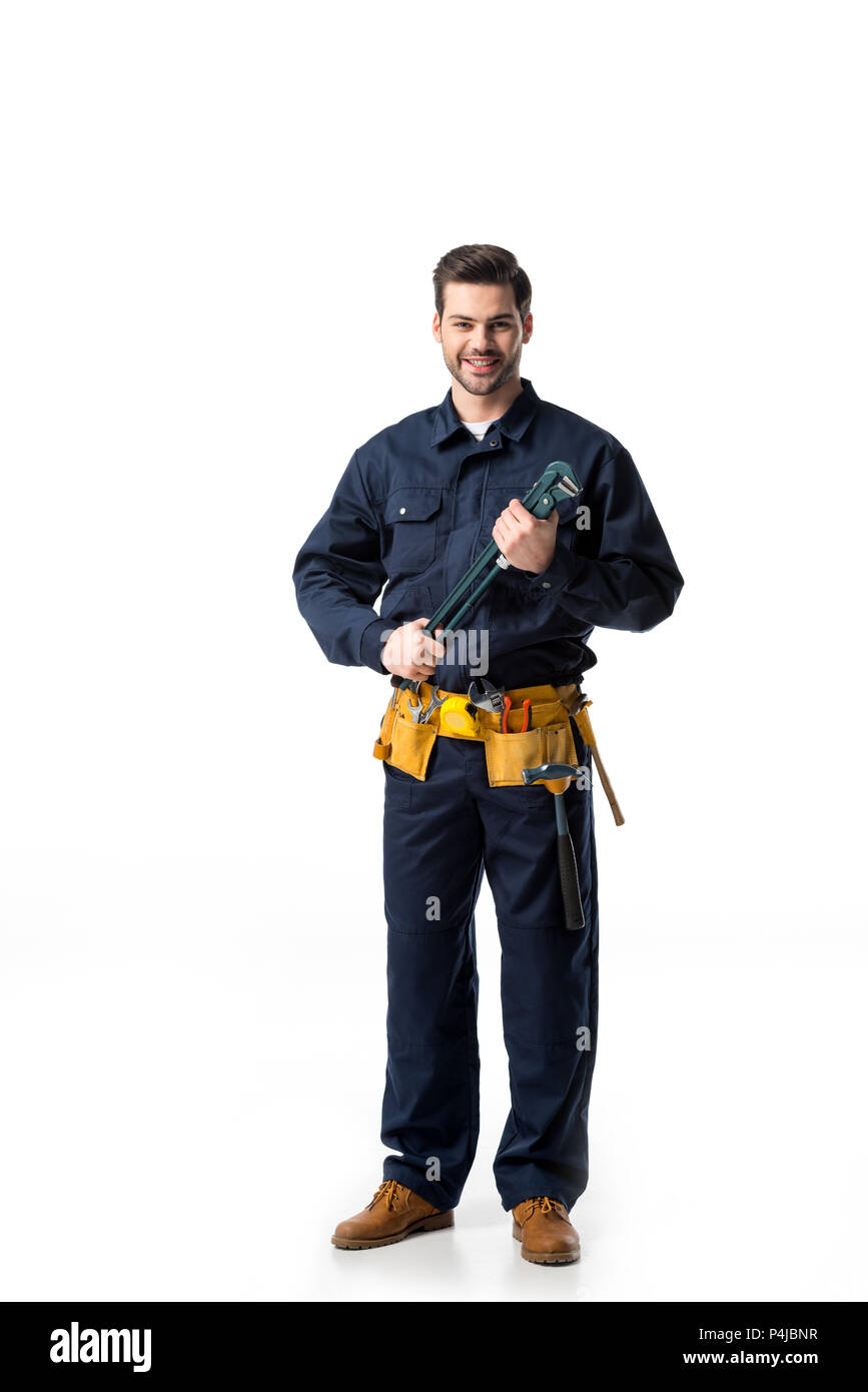 Confident handyman wearing uniform with tool belt and holding wrench ...