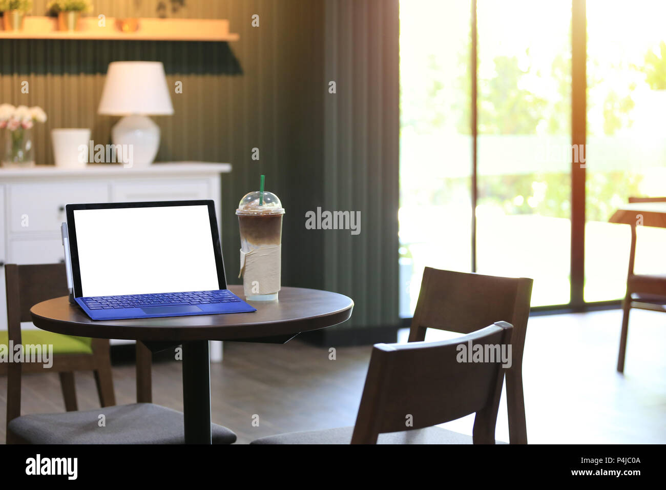Empty screen of laptop and cold coffee mug placed on a food table in a ...