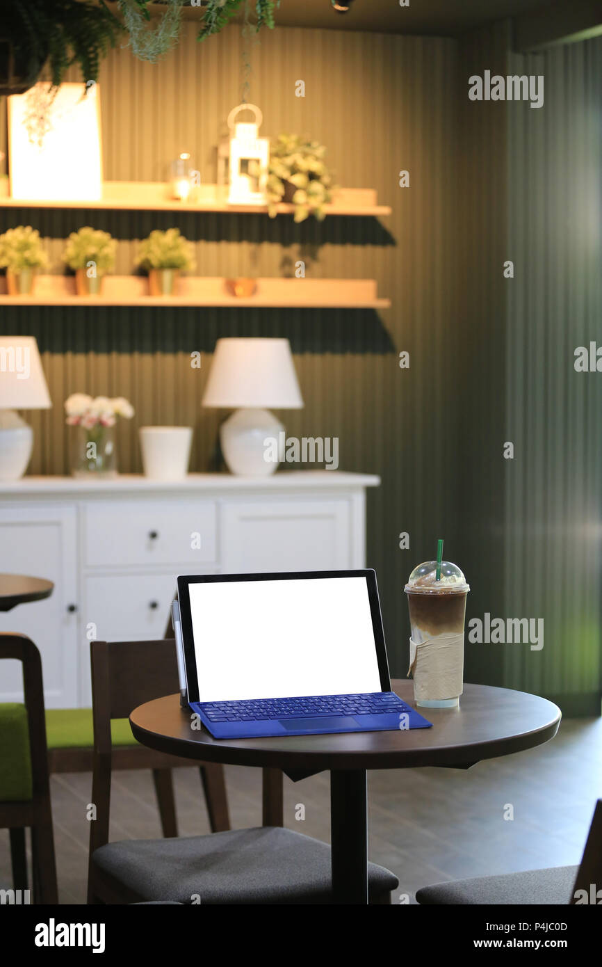 Empty screen of laptop and cold coffee mug placed on a food table in a ...