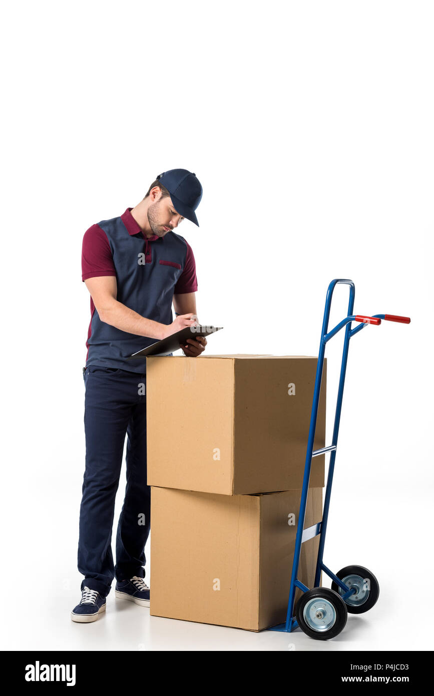 delivery man in uniform checking notes in notepad with cardboard boxes ...