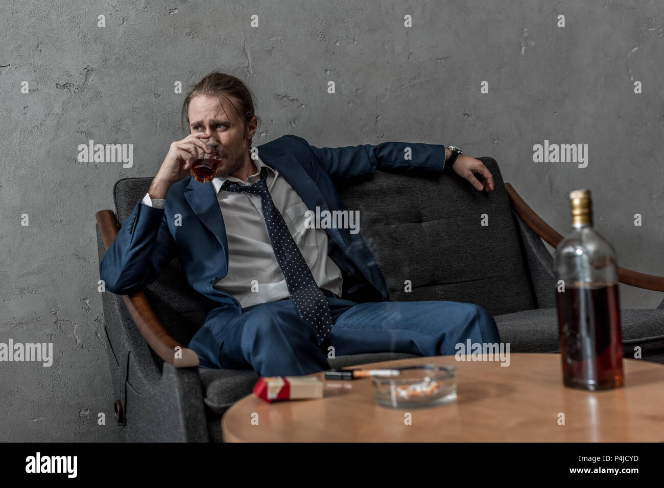 alcohol addicted businessman drinking whiskey while sitting on couch ...