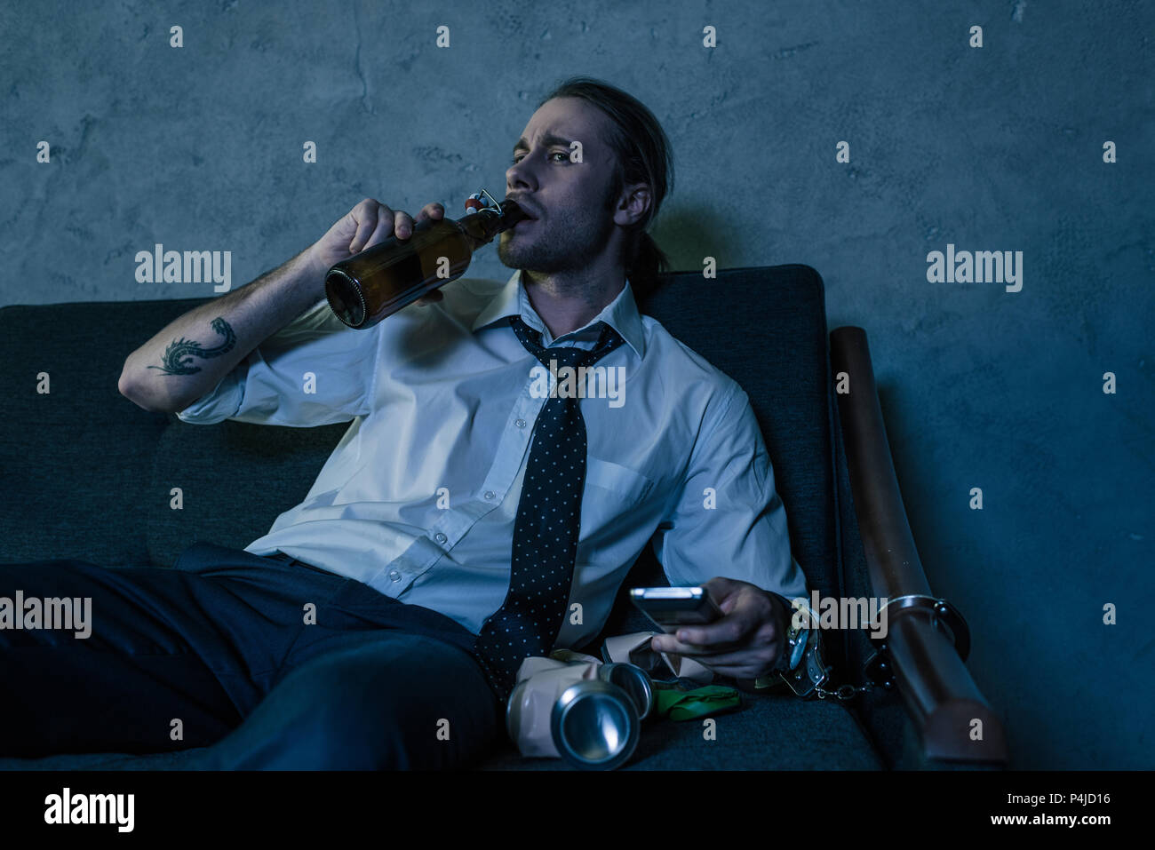 young alcohol addicted man in white shirt watching tv and drinking beer ...