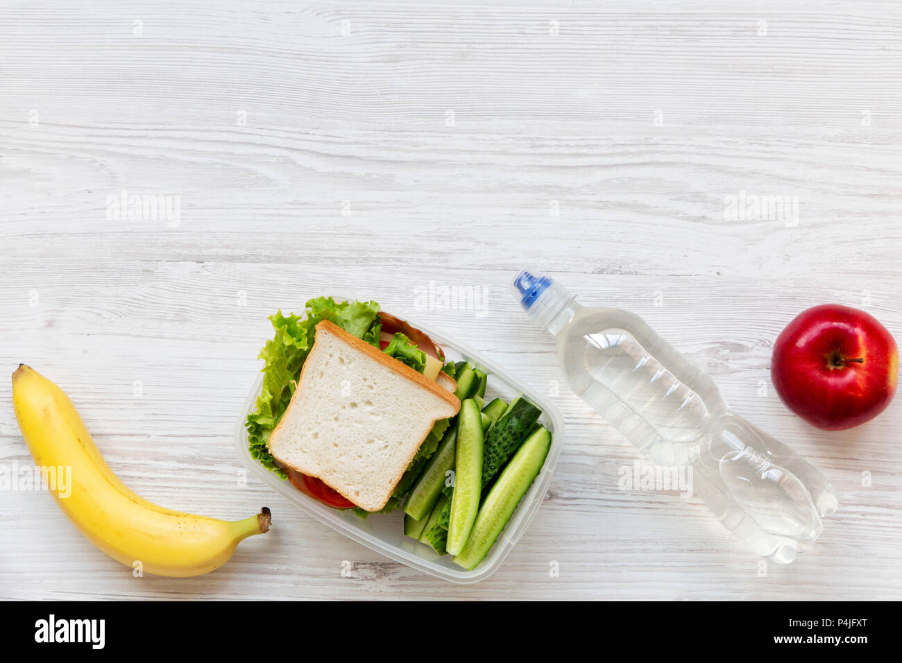 top view school lunch box with sandwich, fruits and bottle of water on ...