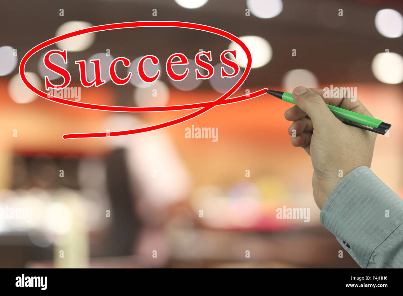 Hand of a businessman holding a red pen writing a success text on blur ...