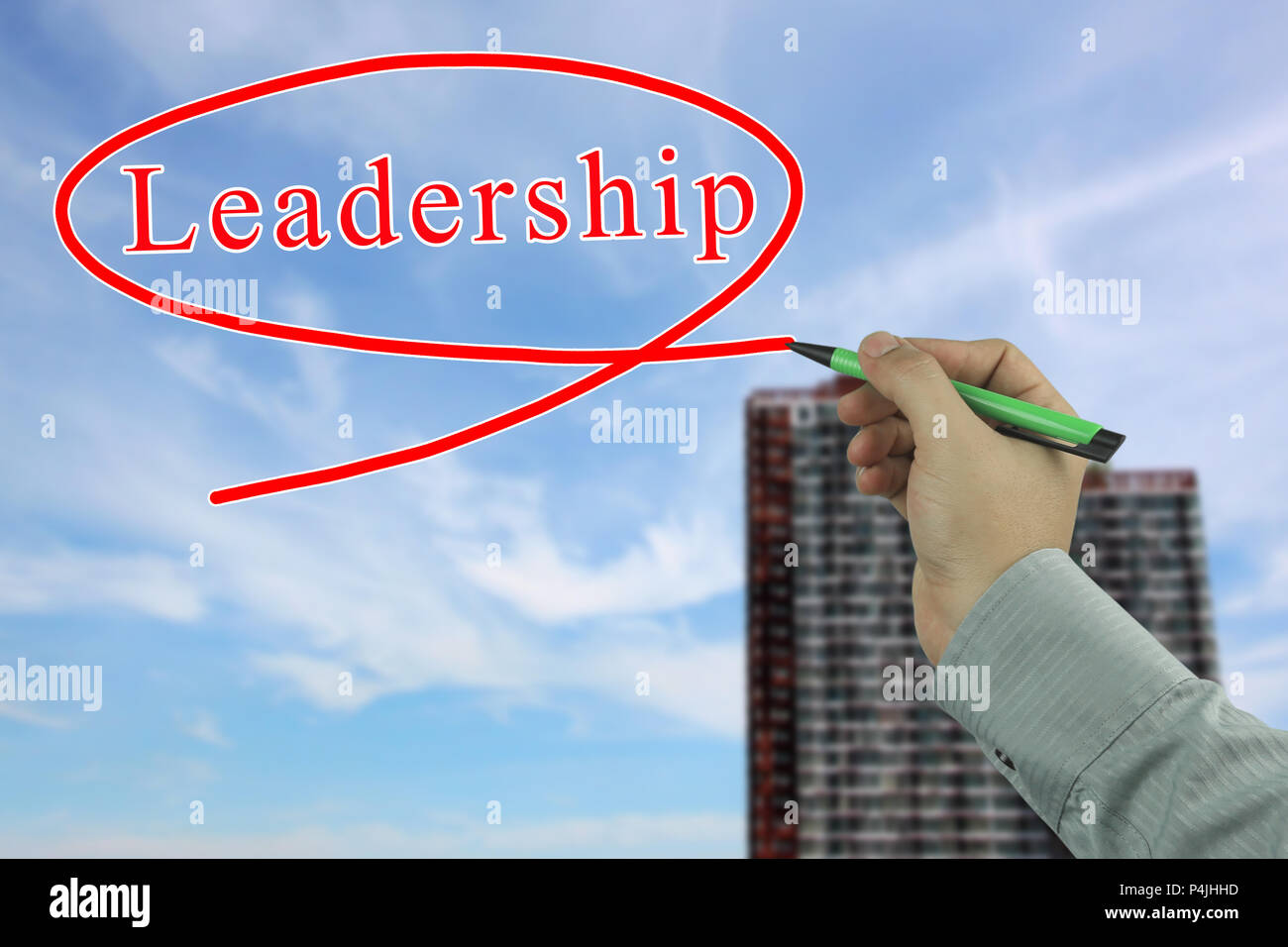 Hand of businessman writing a leadership text on blur skyscraper ...