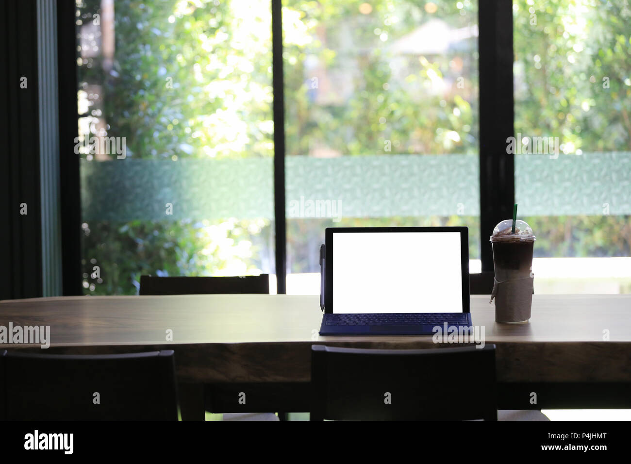 Empty screen of laptop and cold coffee mug placed on a food table in a ...