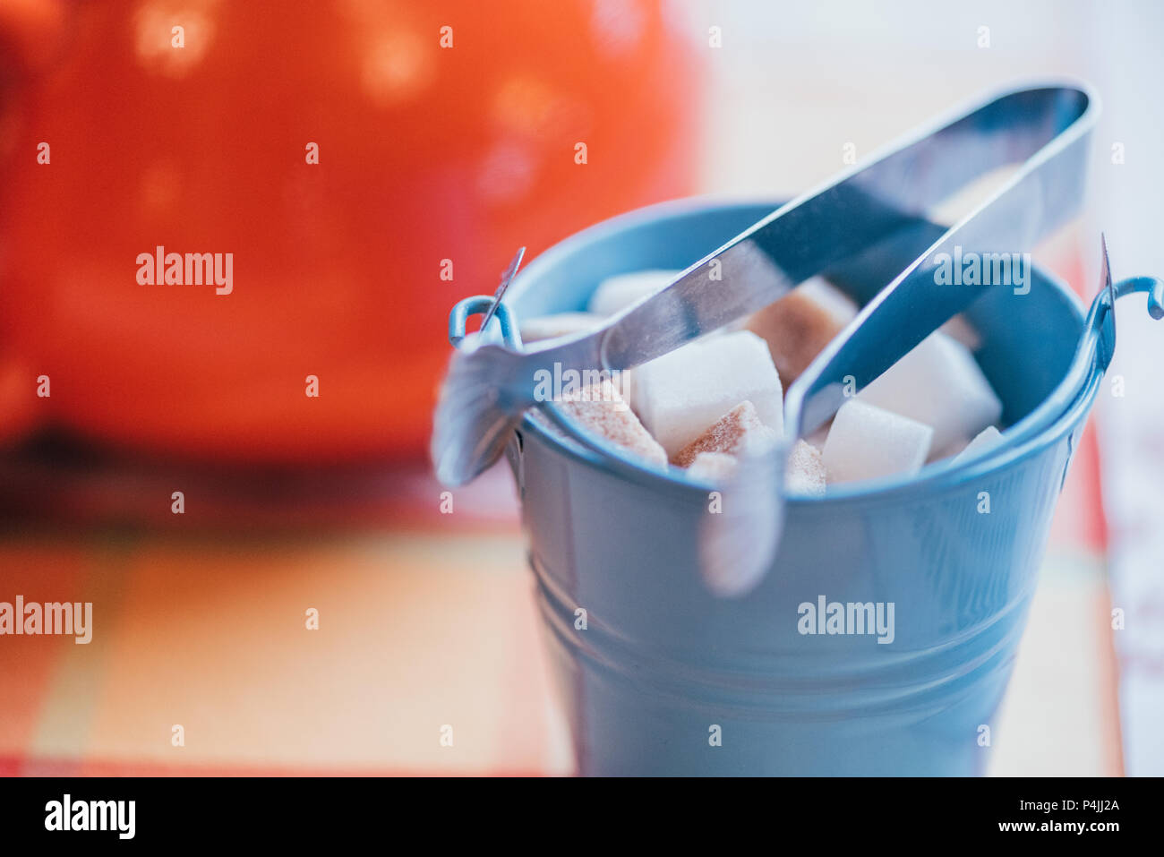 close-up view of small decorative bucket with sugar and tongs on table ...