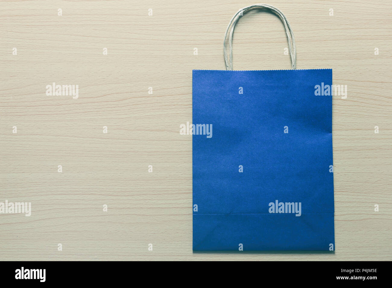 Blue Paper bag is placed on a brown wooden floor and have copy space ...