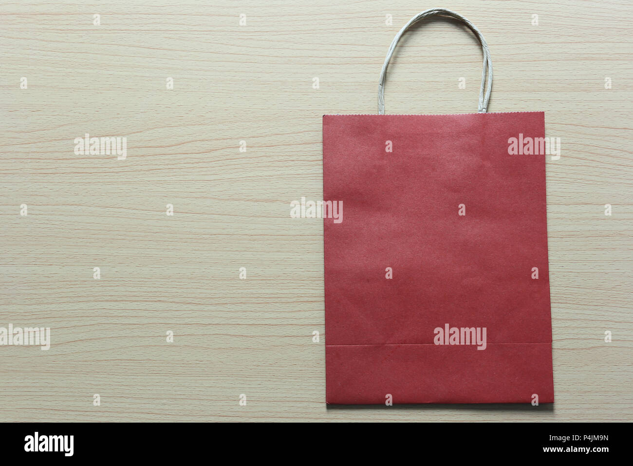 Red Paper bag is placed on a brown wooden floor and have copy space for ...