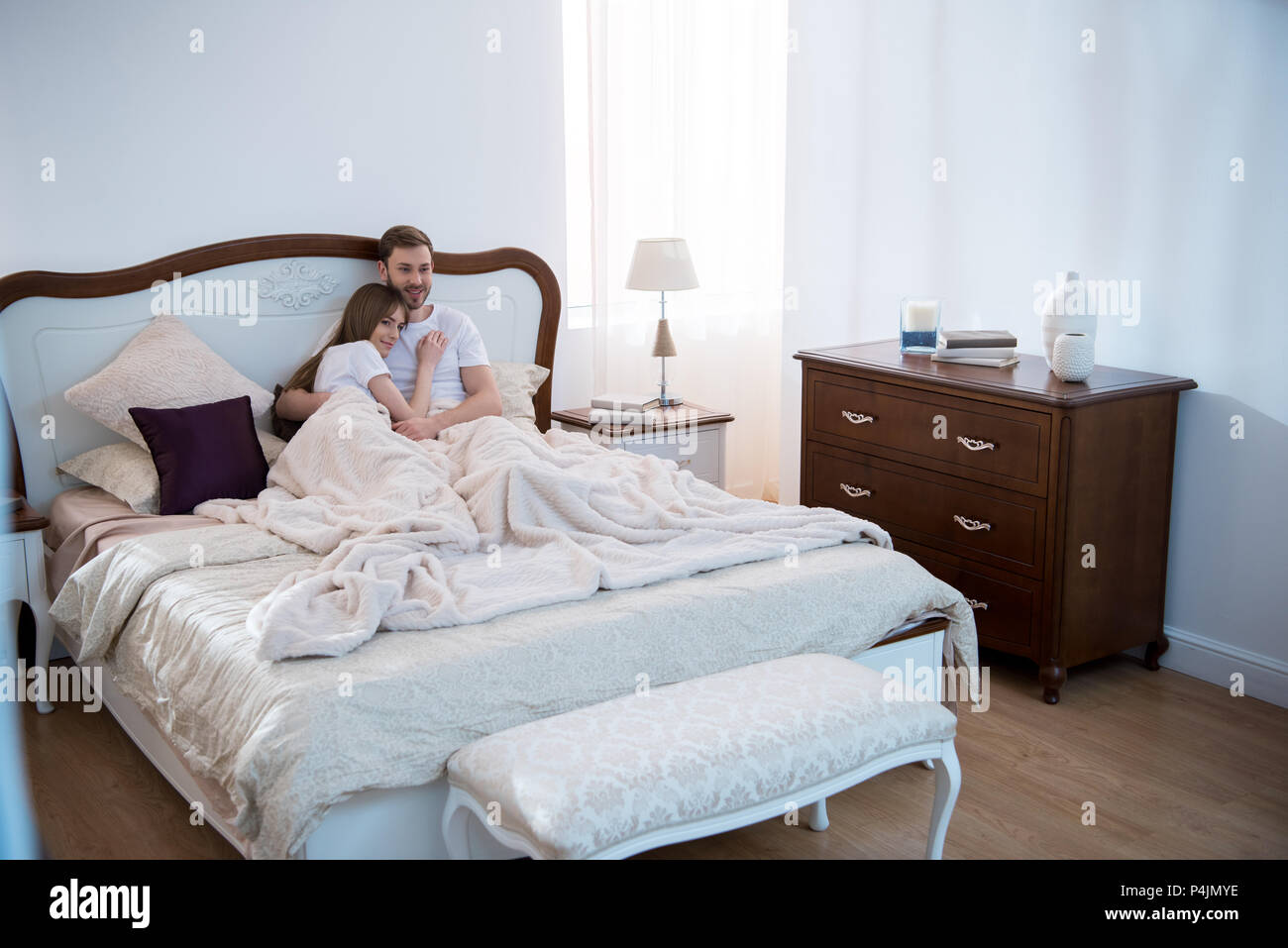 Young woman lying on her boyfriend chest in bedroom with modern ...