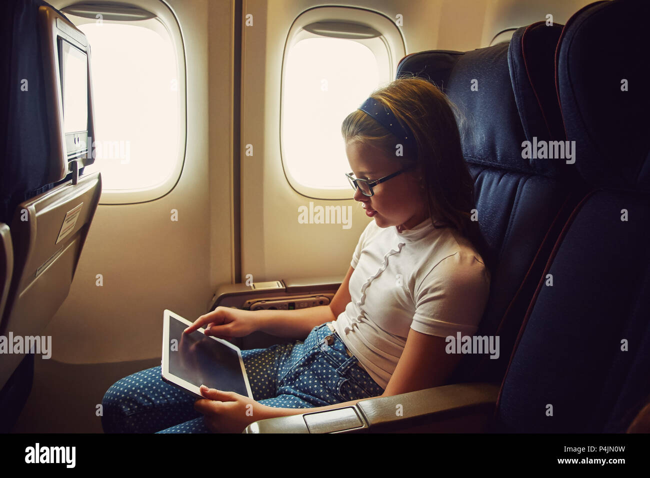 little girl in a chair on board an airplane with tablet computer Stock ...