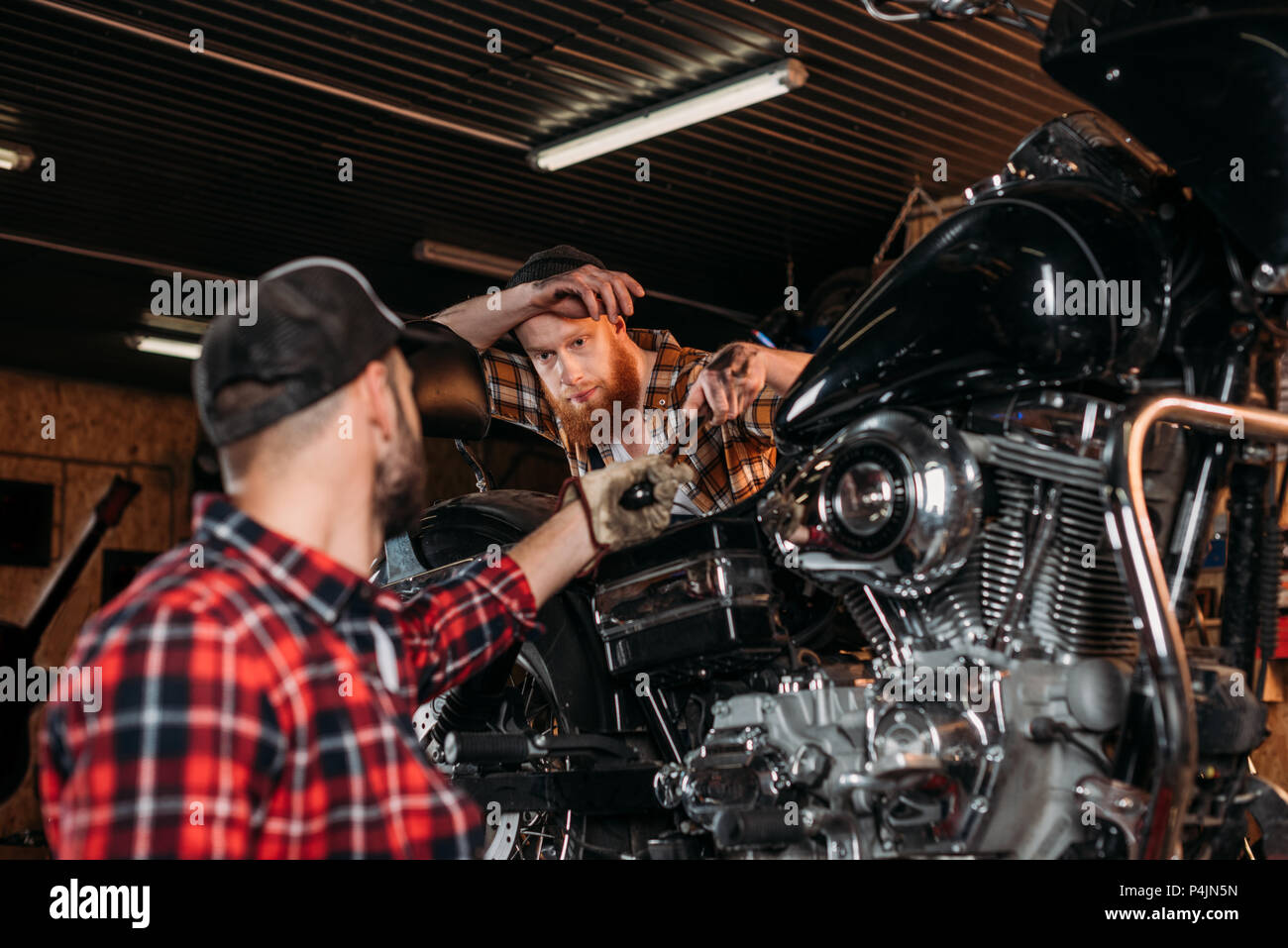 handsome mechanics repairing motorcycle together at custom garage Stock ...