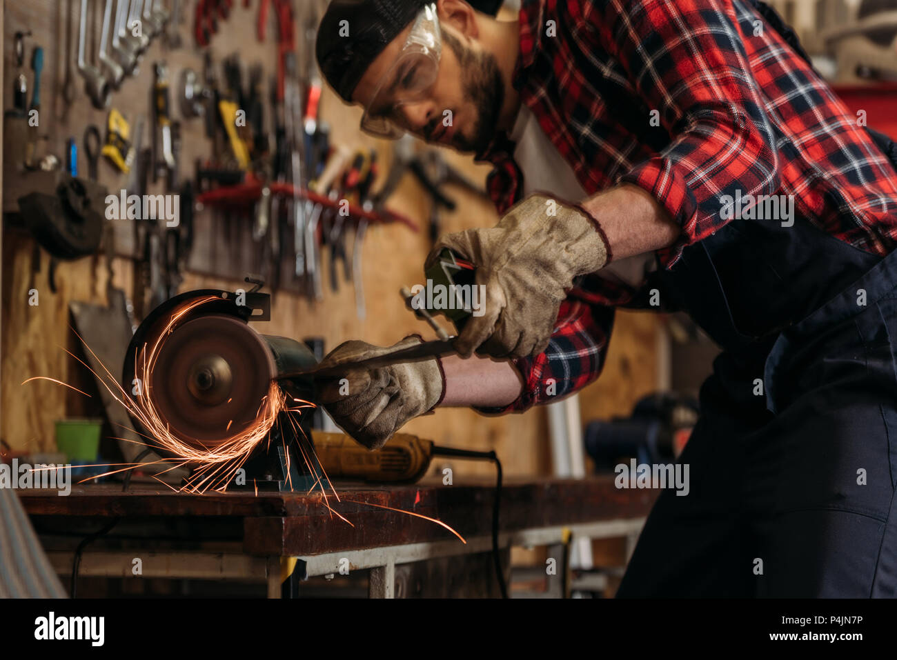 young repair workshop worker using grinding machine at garage Stock ...