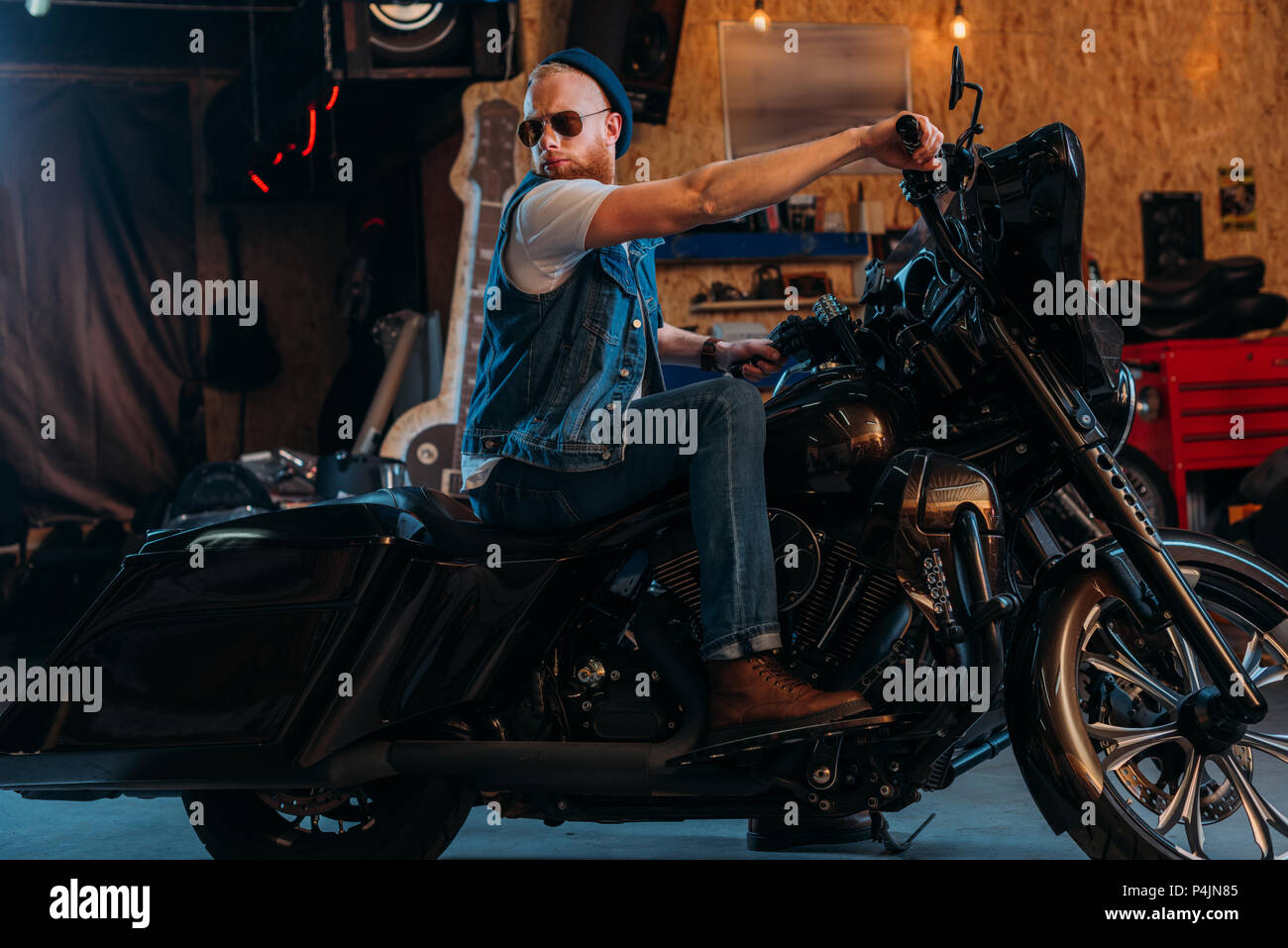 handsome young man sitting on motorcycle at garage Stock Photo - Alamy