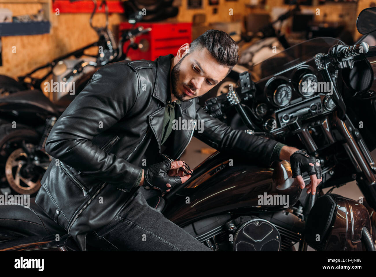 stylish rockabilly man sitting on bike at garage Stock Photo - Alamy