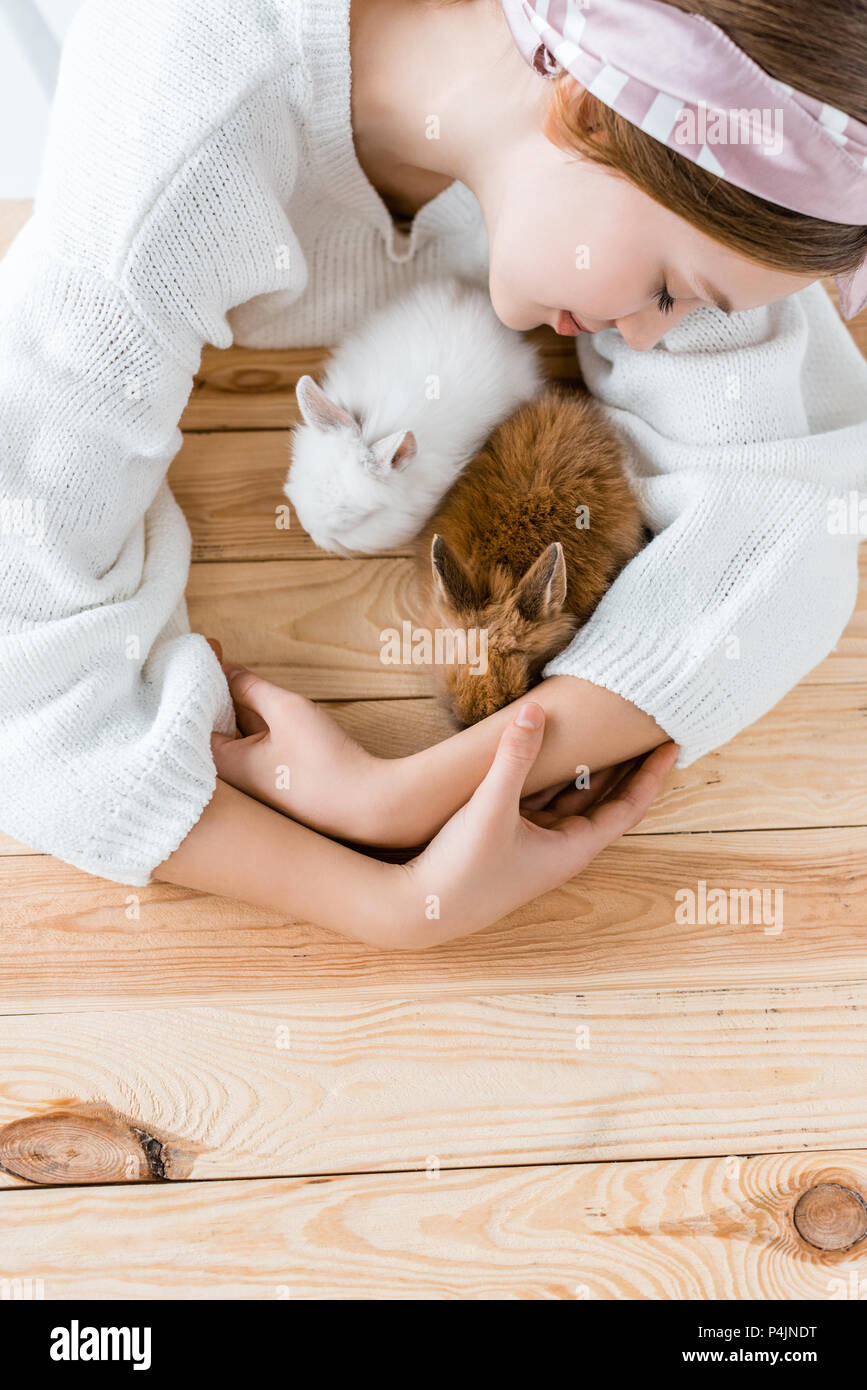 top view of girl hugging cute furry rabbits at wooden table Stock Photo ...
