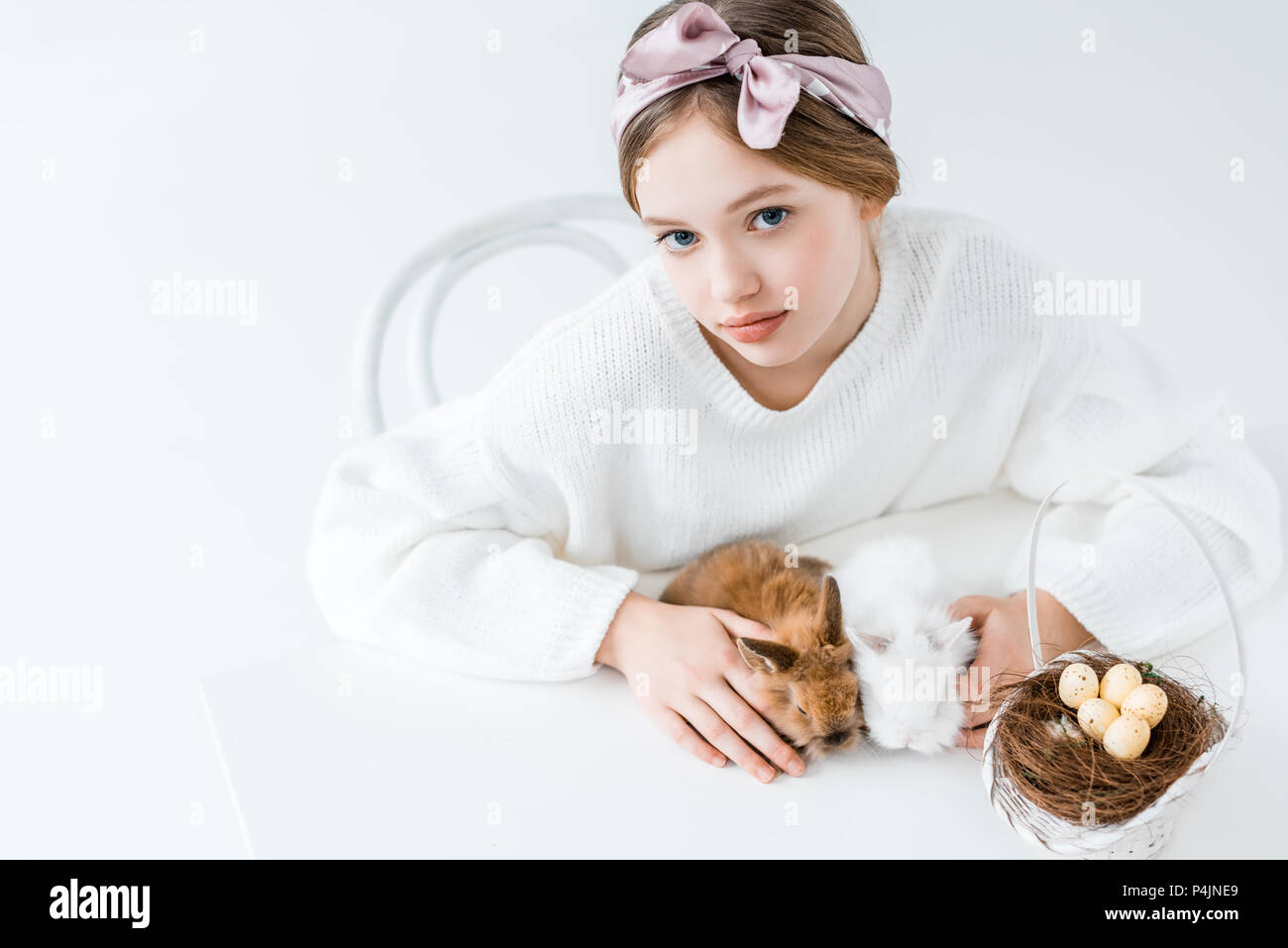 beautiful girl looking at camera while sitting with furry rabbits and ...