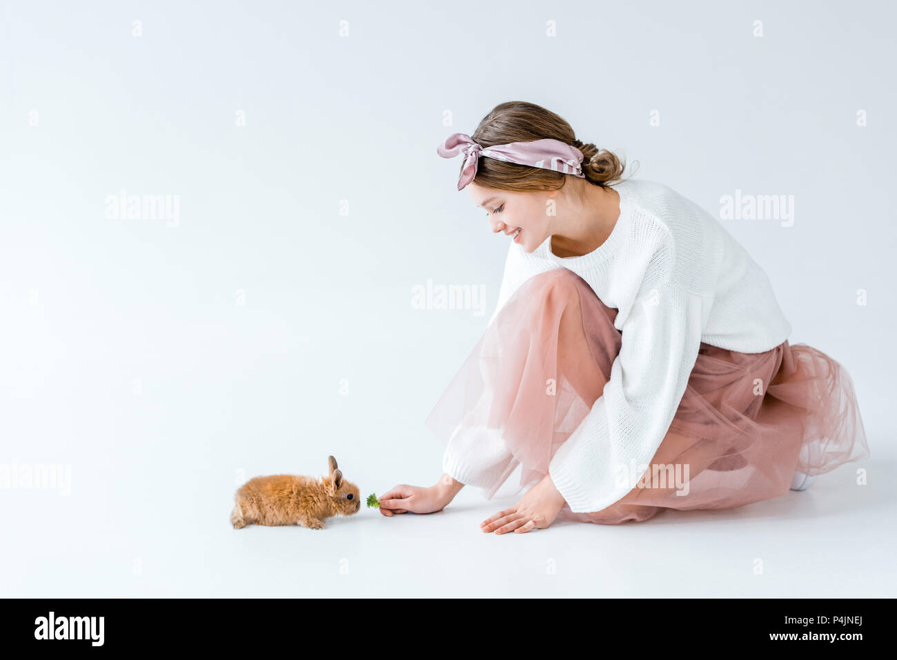 side view of beautiful smiling girl feeding furry rabbit isolated on ...