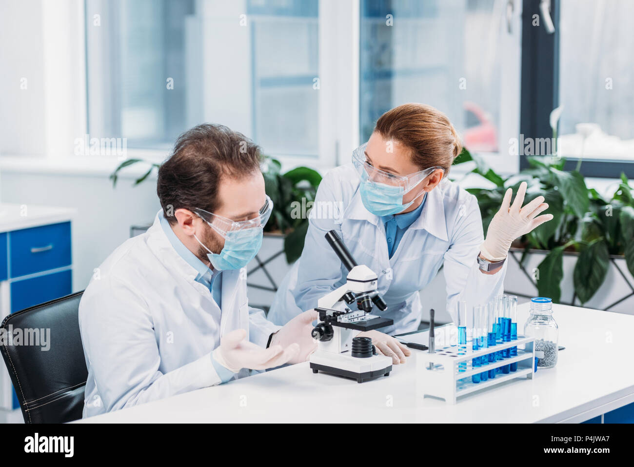 scientists in medical masks and goggles working on scientific research ...