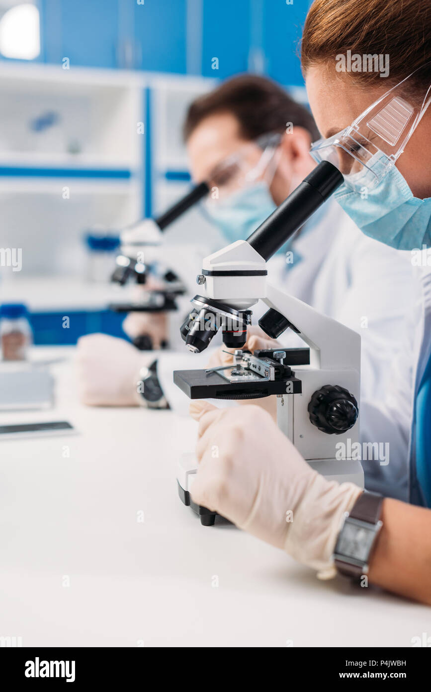 selective focus of scientists in medical masks and goggles looking ...