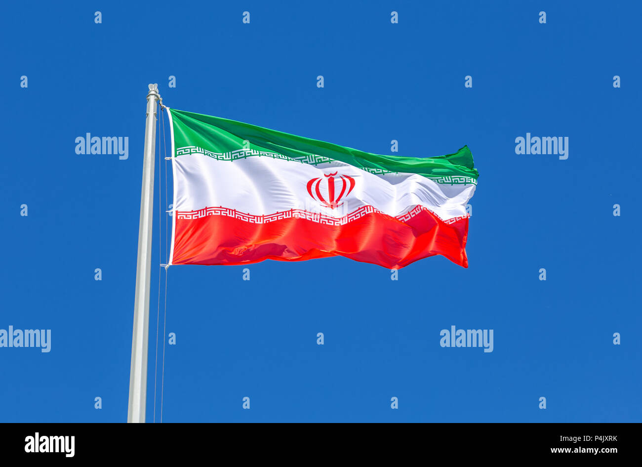 Flag of Iran waving in the wind against the blue sky Stock Photo - Alamy