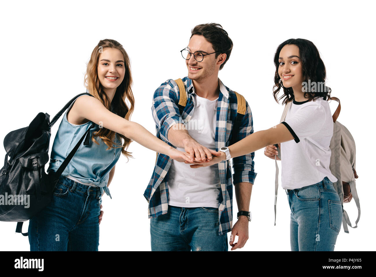 happy multicultural students putting hands together isolated on white ...
