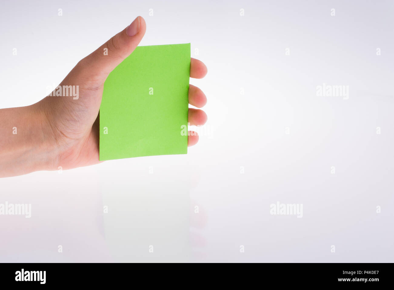 Hand holding a light green color rectangular paper on a white ...