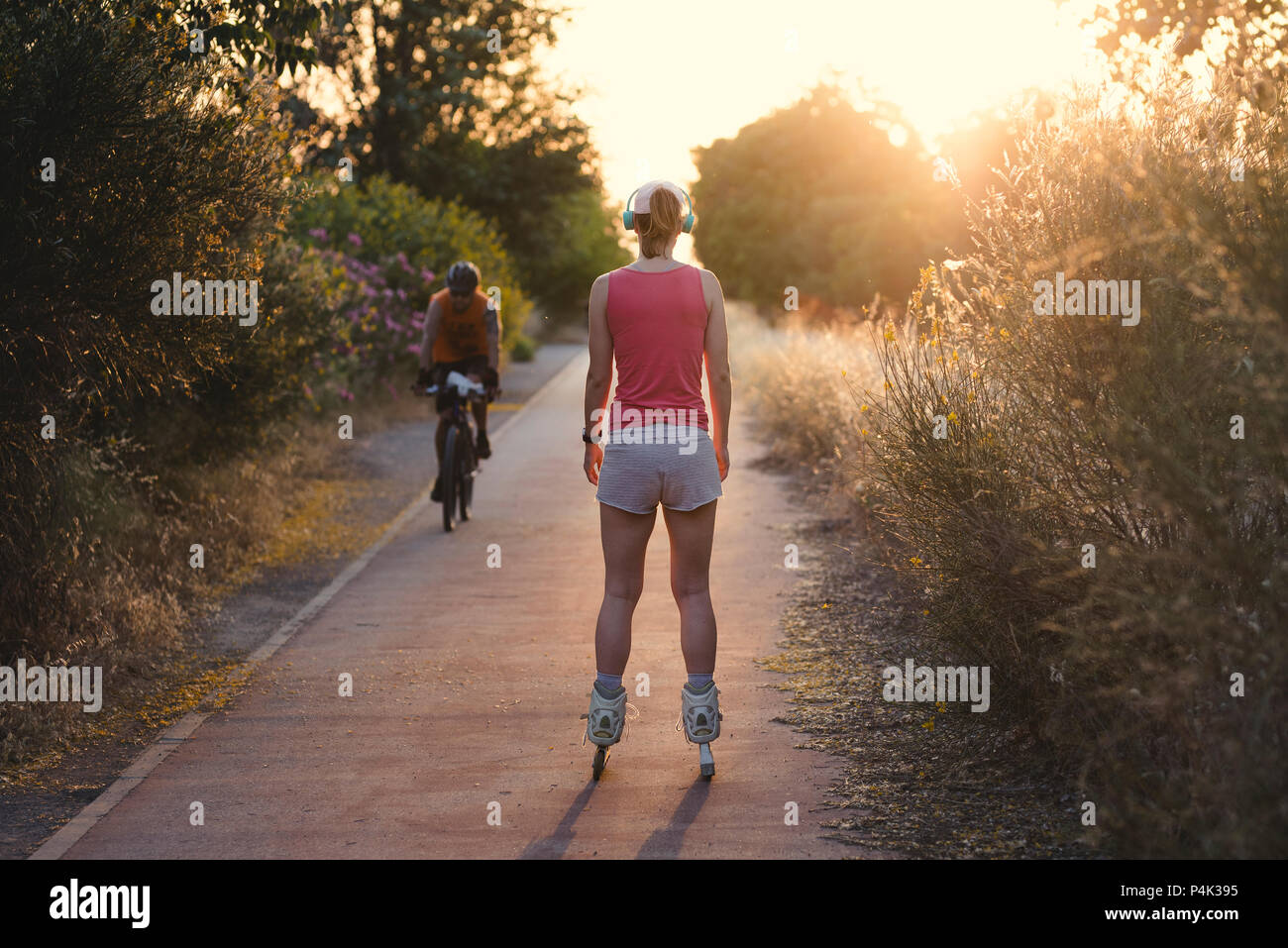 Young woman having fun while roller skating outdoors during sunset ...