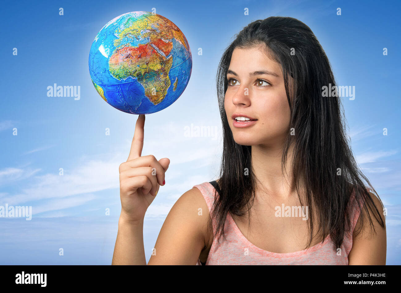 Pretty young brunette girl smiling and balancing a world globe in her ...