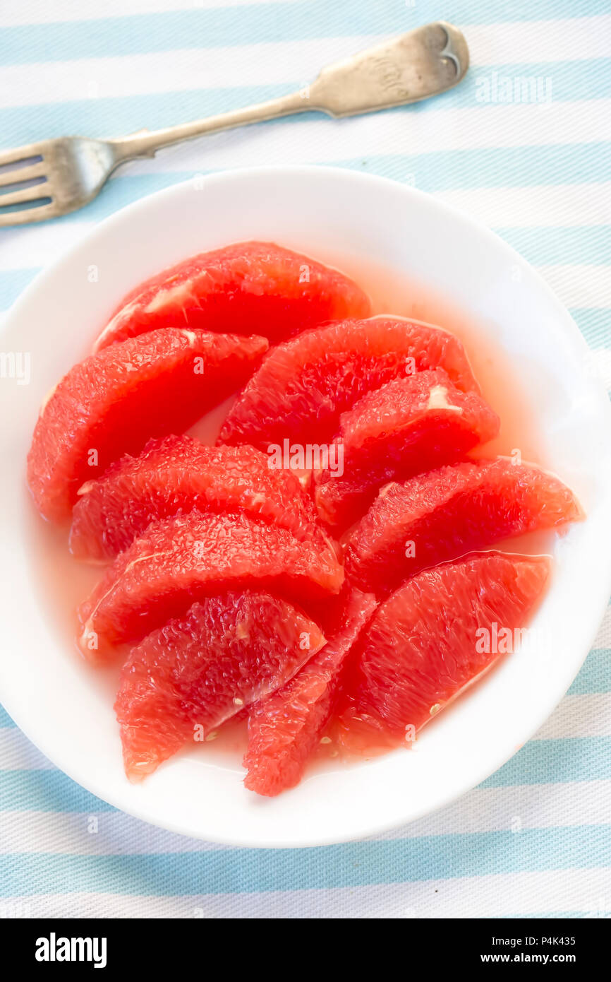 Red grapefruit pieces, segments on white plate Stock Photo - Alamy