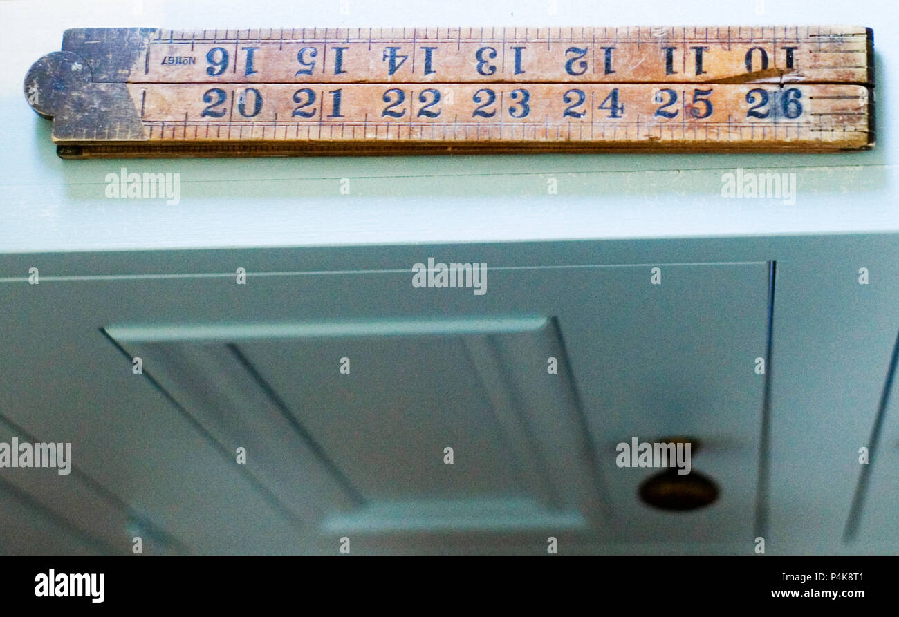 A wooden ruler is placed on a cabinet to be installed in a kitchen in a ...