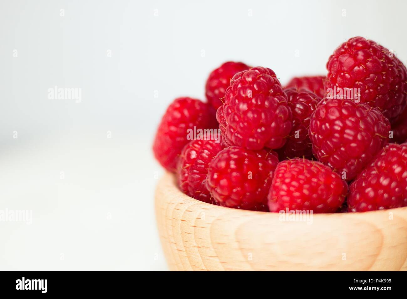 Detail of beautiful raspberries in wooden bowl. Fruit and bowl are ...