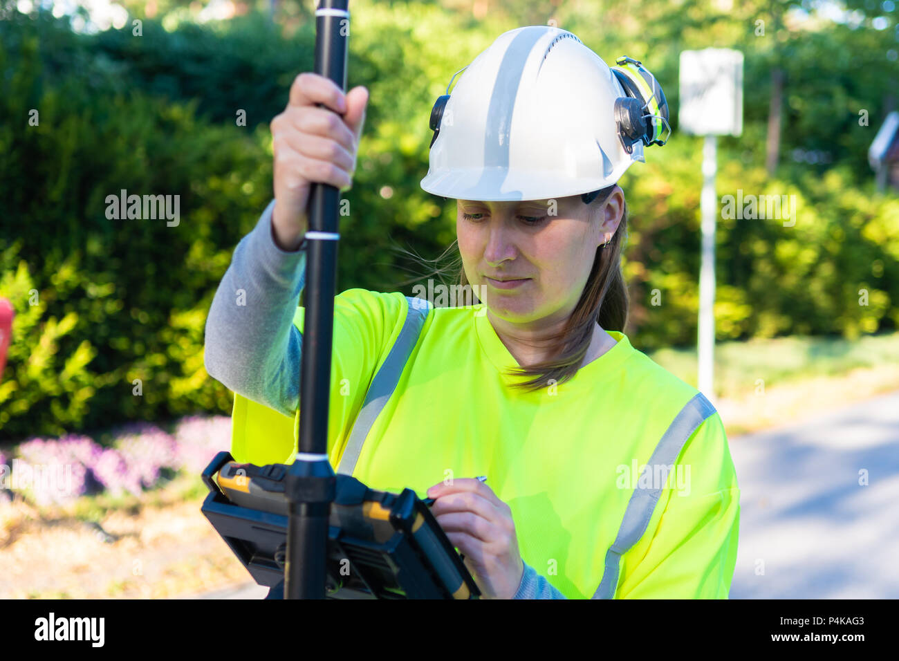 Close up of woman in reflective clothing using GPS land surveying tool ...