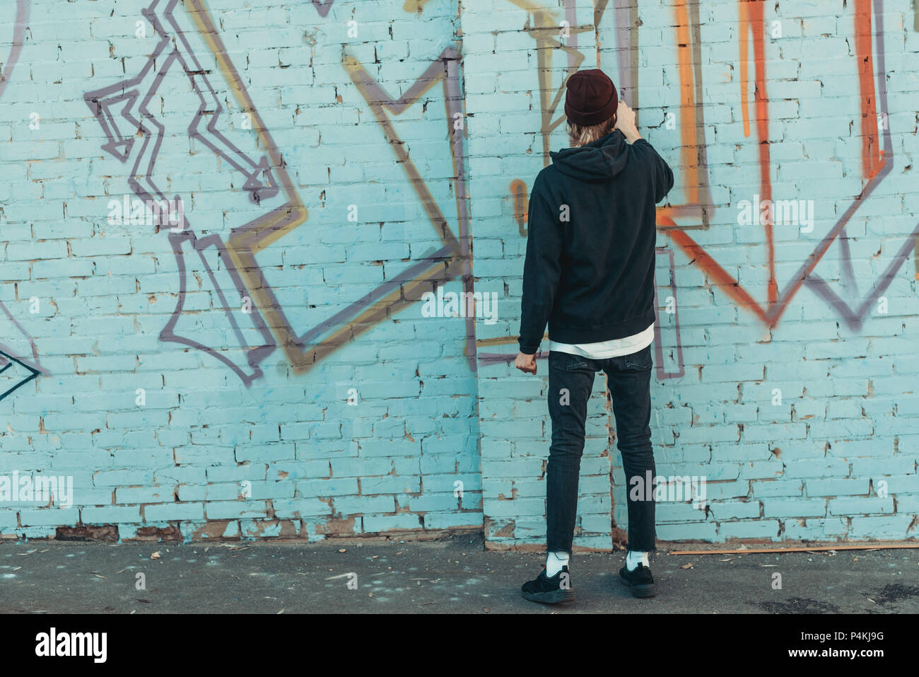 back view of man painting colorful graffiti on wall Stock Photo - Alamy