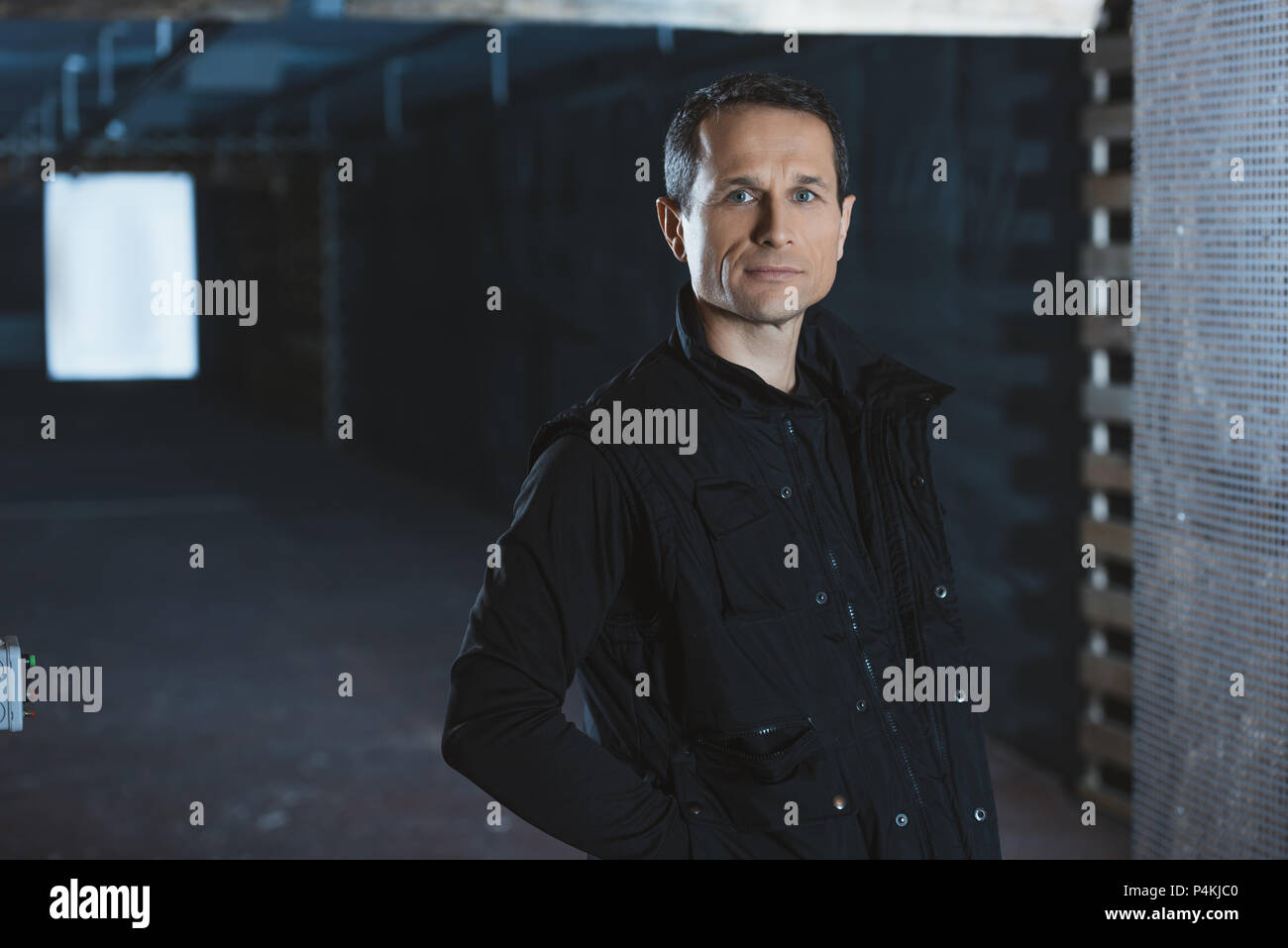 handsome serious man standing in shooting range and looking at camera ...