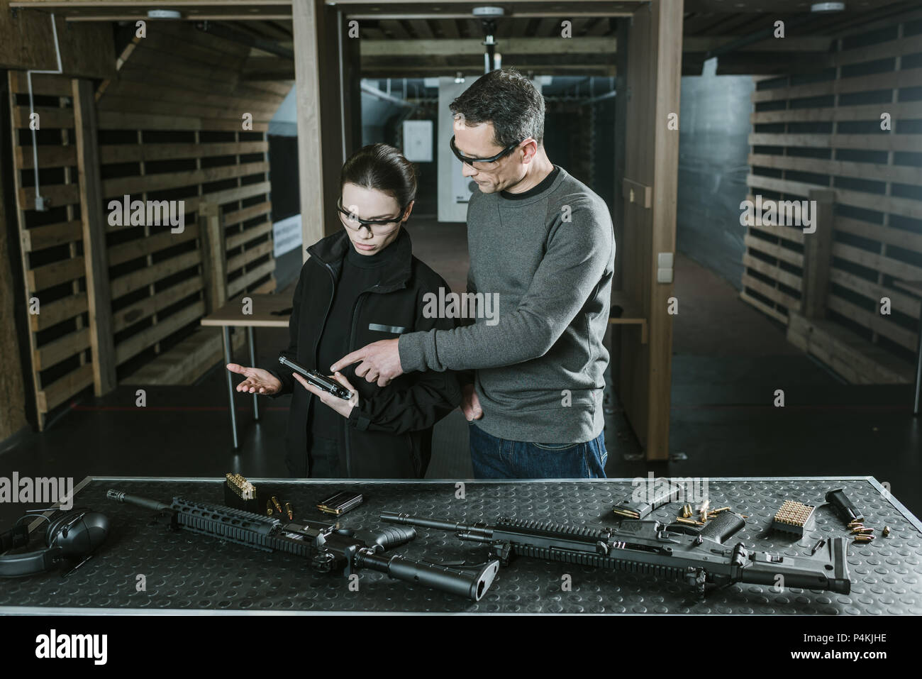 instructor showing pistol to customer in shooting range Stock Photo - Alamy