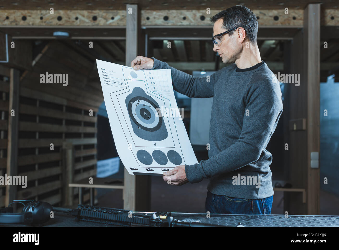 side view of shooter looking at used target after shooting in gallery ...