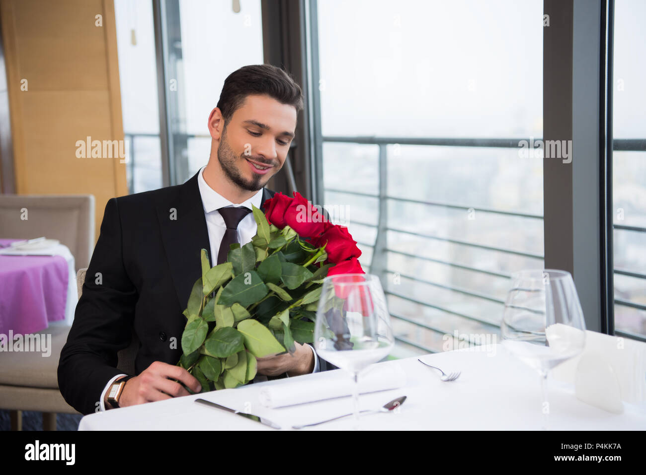 smiling man in suit with bouquet of red roses waiting for girlfriend in ...