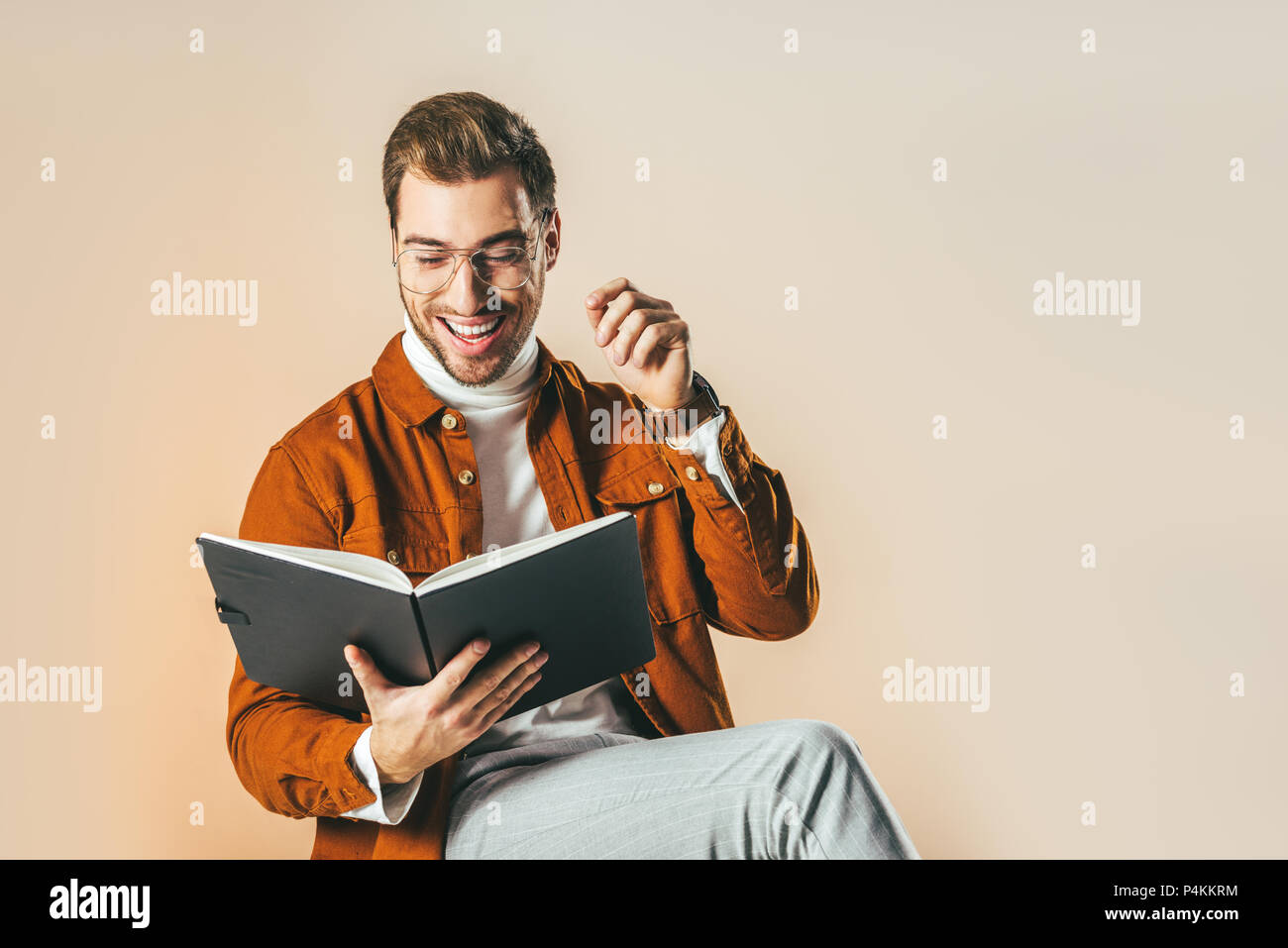 portrait of cheerful man reading notebook isolated on beige Stock Photo ...