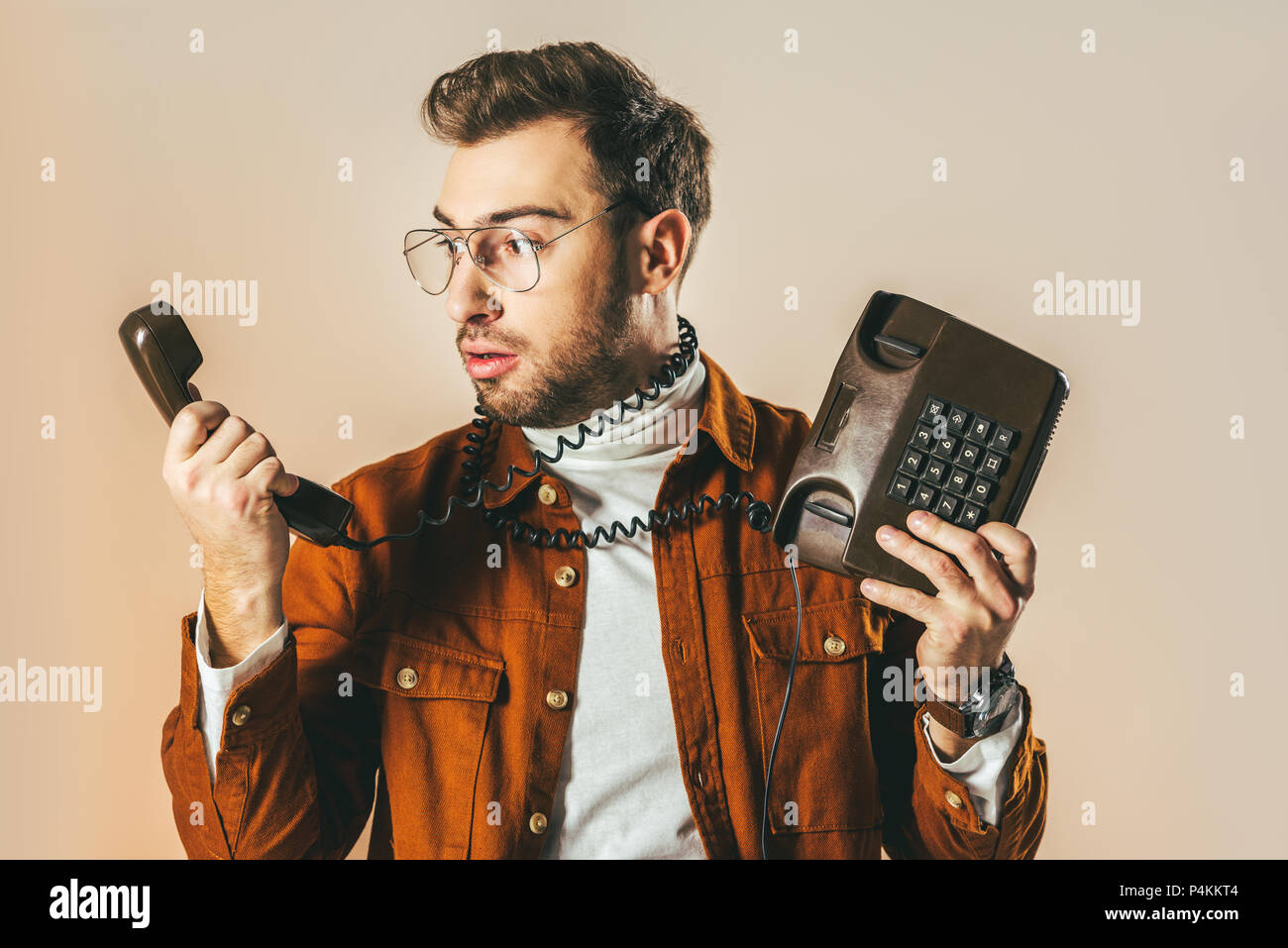portrait of shocked man with telephone cable around neck looking at ...