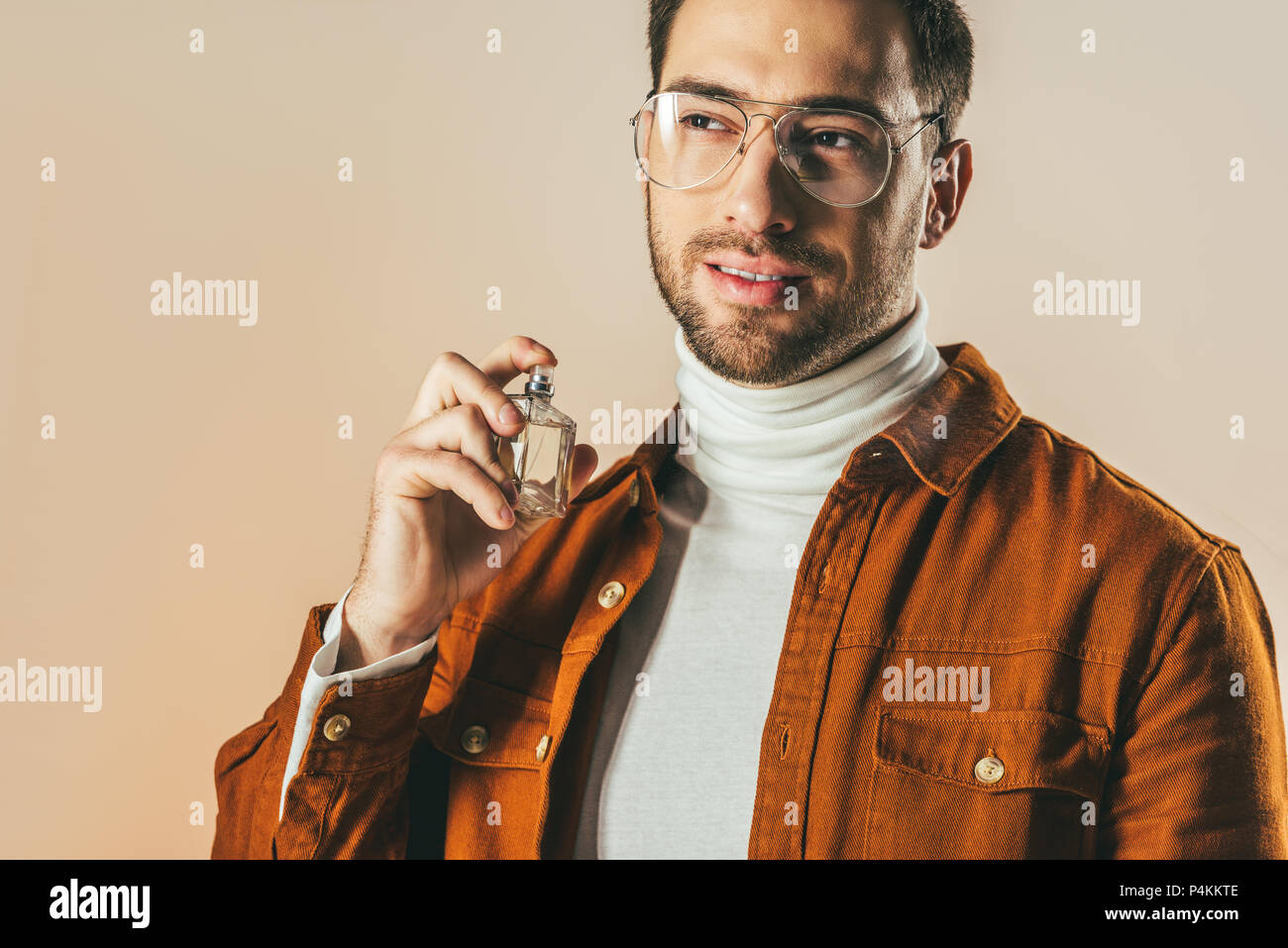 portrait of stylish young man applying perfume isolated on beige Stock ...