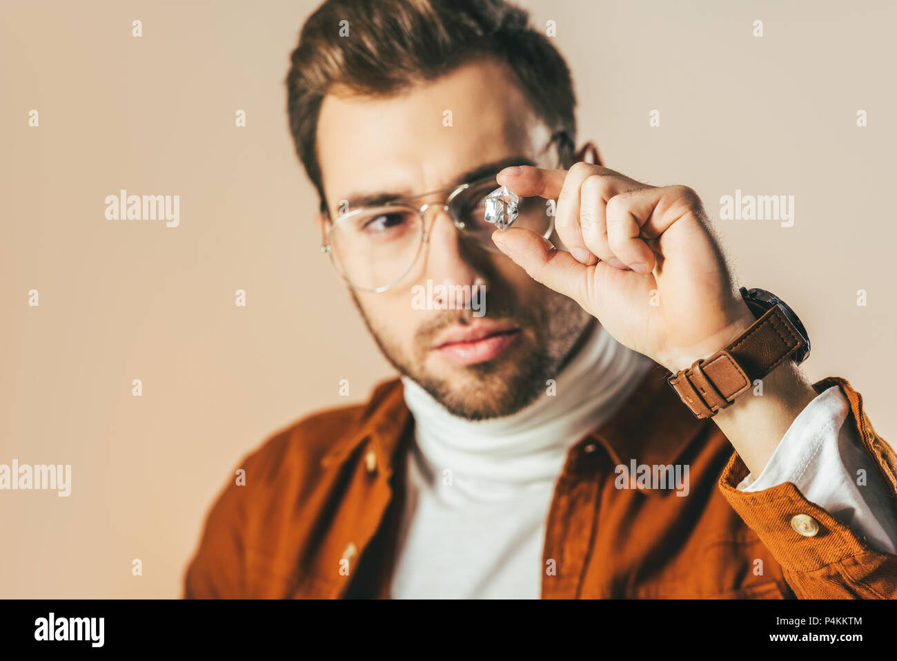 selective focus of fashionable man looking at diamond in hand isolated ...