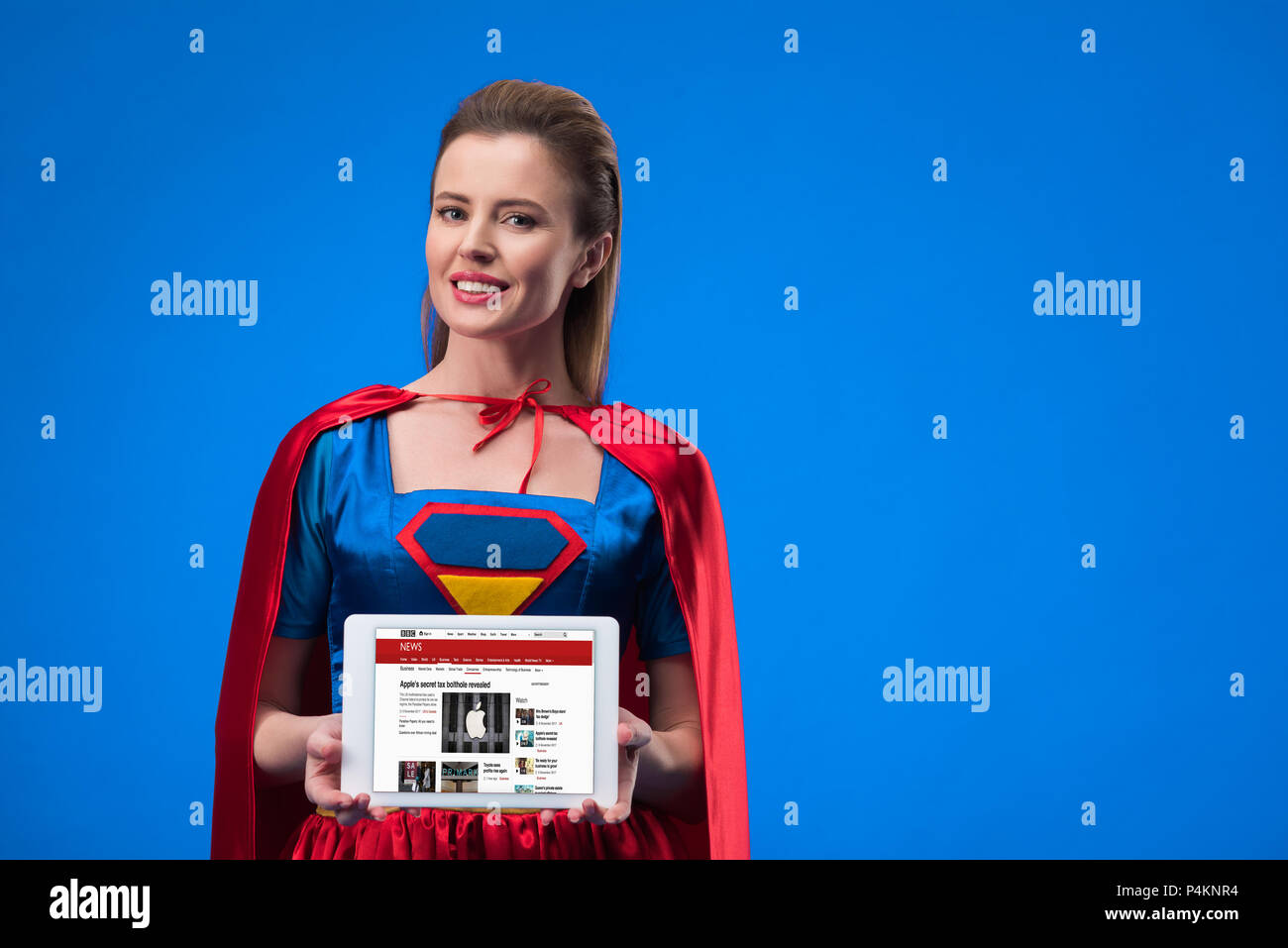 portrait of cheerful woman in superhero costume showing tablet isolated ...