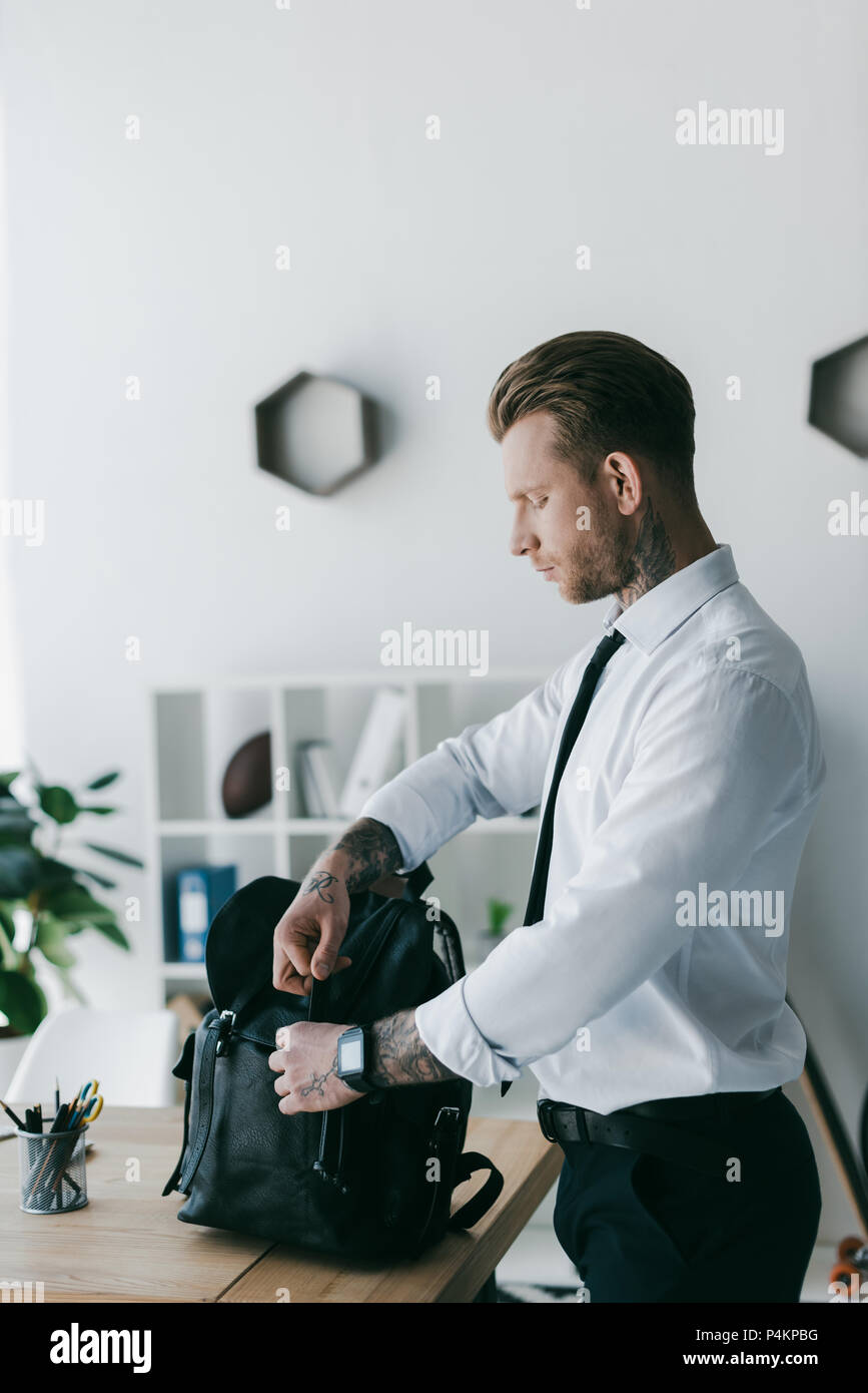side view of young businessman opening backpack at workplace Stock ...